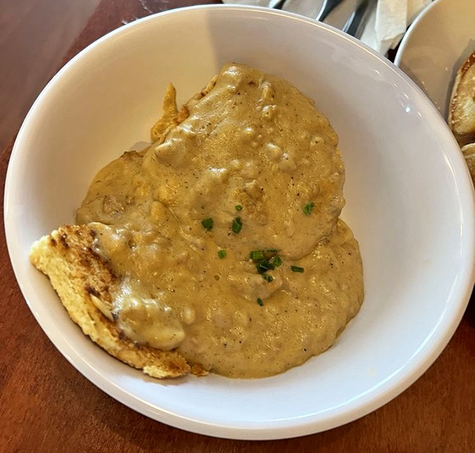 Southern comfort in a bowl: creamy biscuits and gravy with a sprinkle of chives—the kind of dish that makes you want to linger over coffee all morning.