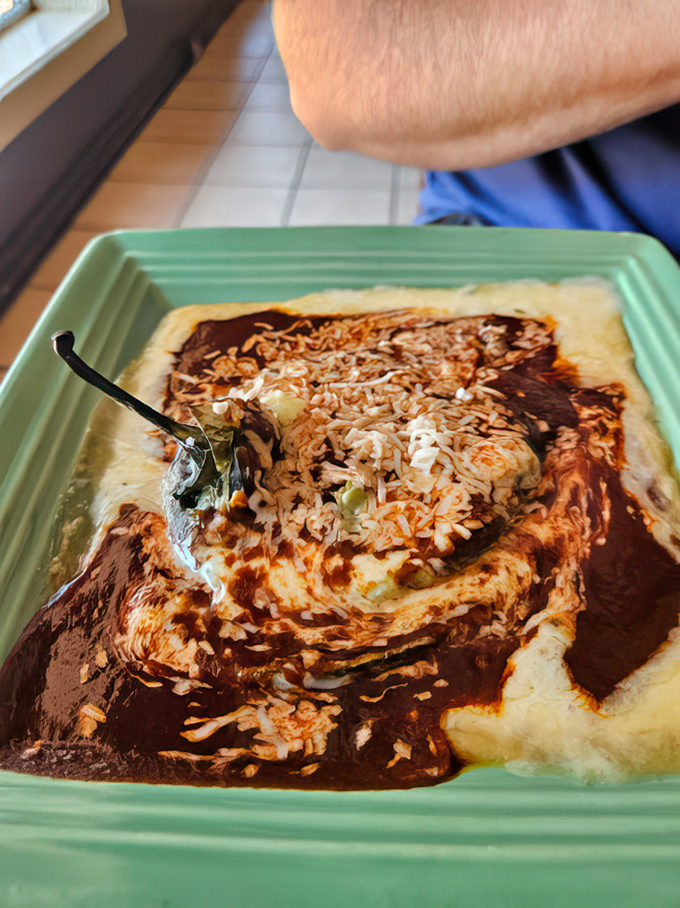 This chile relleno isn't just stuffed—it's having an identity crisis in the best way possible, swimming in a sauce worth bottling and taking home.