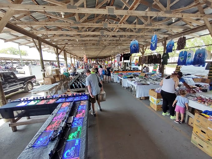 The covered market's wooden beams frame a shopper's paradise, where racks of clothing and tables of merchandise create a labyrinth of potential discoveries.