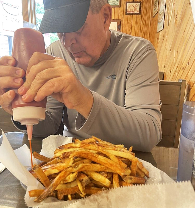 The sacred ritual of condiment application—this gentleman knows that proper hot dog dressing is serious business requiring full concentration.