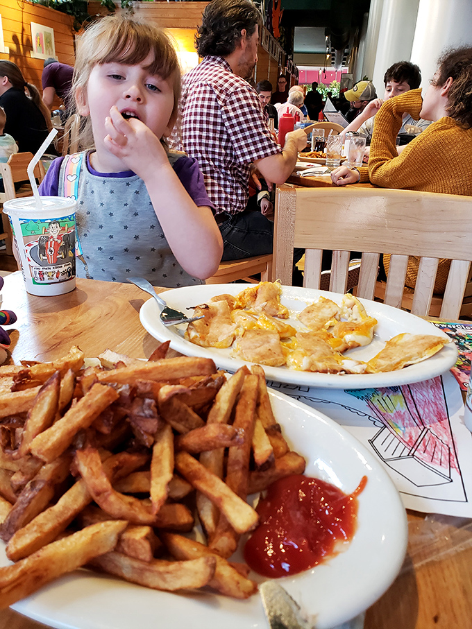Family dining at its finest—where memories are made between bites of comfort food. That kid's face says it all: French fry happiness is universal.