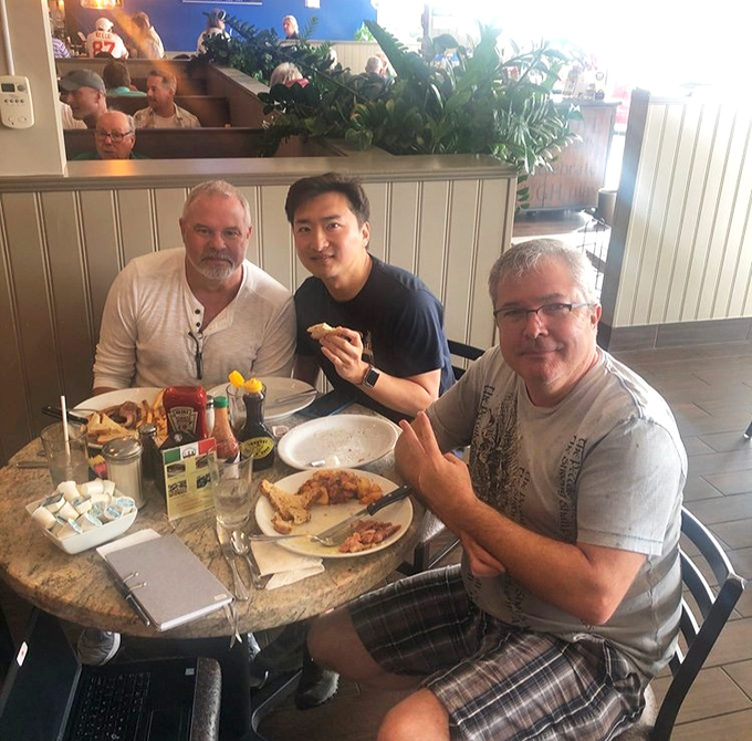 Happy diners sharing a meal and conversation—the universal language of "this food is too good to talk about until we've finished every bite."