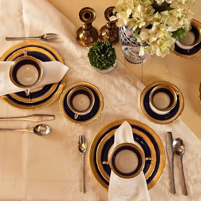 Elegant table settings with gold-rimmed china and fresh flowers create a warm inviting atmosphere perfect for gatherings and timeless celebrations.