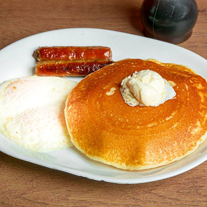 The platonic ideal of a pancake – golden, fluffy, and supporting a melting pat of butter like it was born for this purpose.