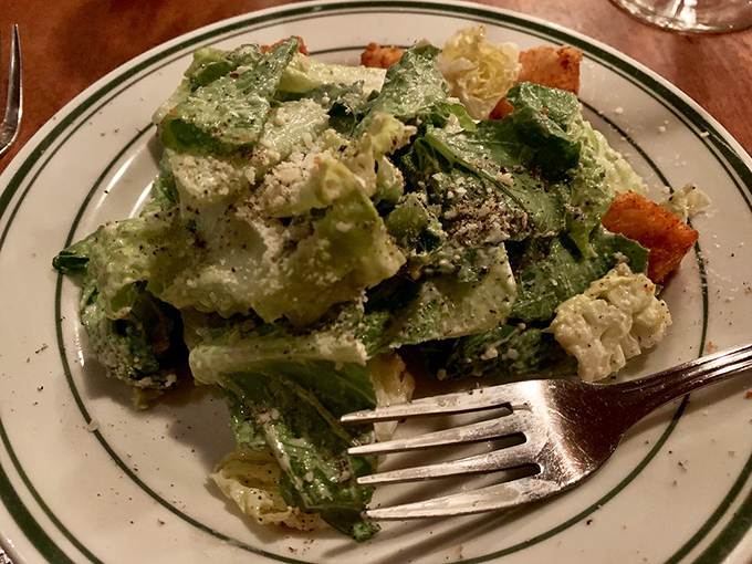 The Caesar salad provides the illusion of virtue before the meat parade begins—a crisp, creamy prelude to the main event.