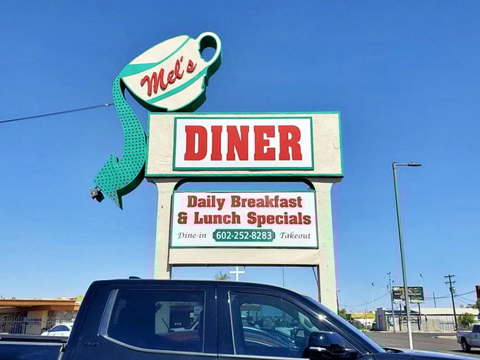 That giant coffee cup sign isn't just cute – it's a beacon guiding hungry souls to breakfast paradise at Mel's Diner.