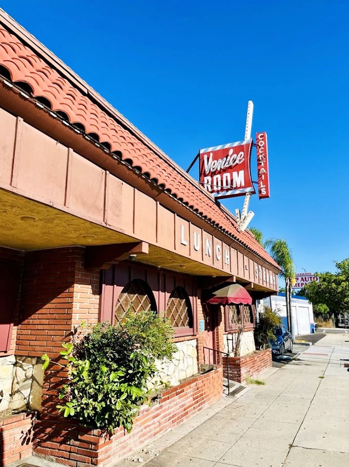 The Venice Room's retro sign promises old-school charm. This pink building houses one of California's most unique dining experiences – you become the chef!