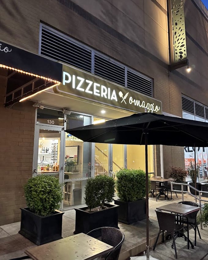 By night, Pizzeria Omaggio glows with possibility – those string lights promising wood-fired magic inside.