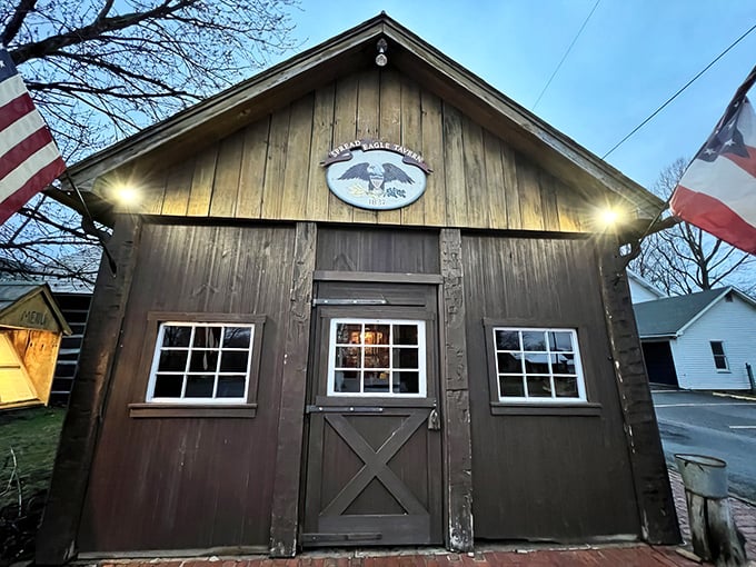 The rustic wooden exterior of Spread Eagle Tavern welcomes visitors with American flags and warm lighting, like a historical postcard come to life.