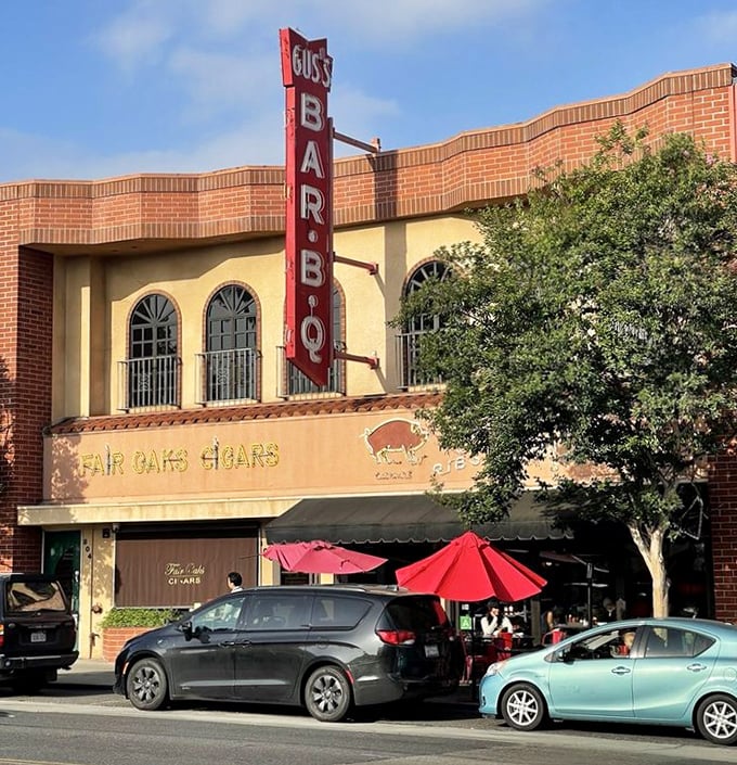 That vertical neon sign isn't just advertising—it's a promise of smoky delights within. The red umbrellas add a touch of casual welcome to this barbecue institution.