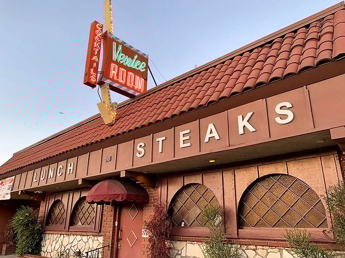 The iconic Venice Room sign glows like a beacon from another era, promising steaks and memories under that distinctive Spanish-style roof.
