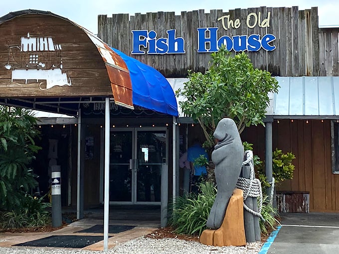 The weathered wooden exterior and iconic manatee statue aren't trying to impress anyone—they're too busy guarding the entrance to seafood paradise.