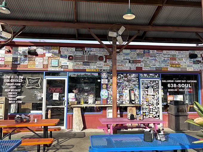 The license plate wall tells a story – each metal rectangle represents a pilgrim who journeyed to this BBQ sanctuary. The colorful picnic tables await your barbecue revelation.