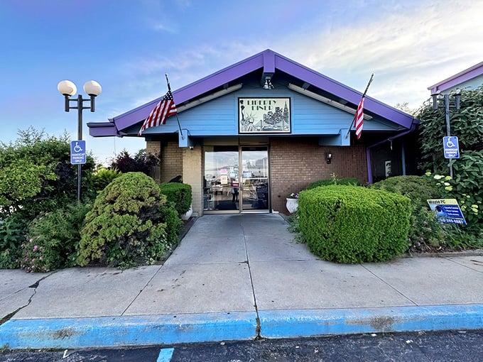 The blue-roofed sanctuary with American flags standing guard – Liberty Diner's modest exterior belies the culinary treasures waiting inside.