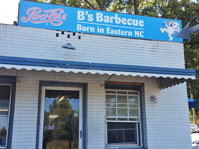 The blue sign says it all: "Born in Eastern NC." No website, no fancy marketing—just a white brick building that's become a barbecue pilgrimage site.