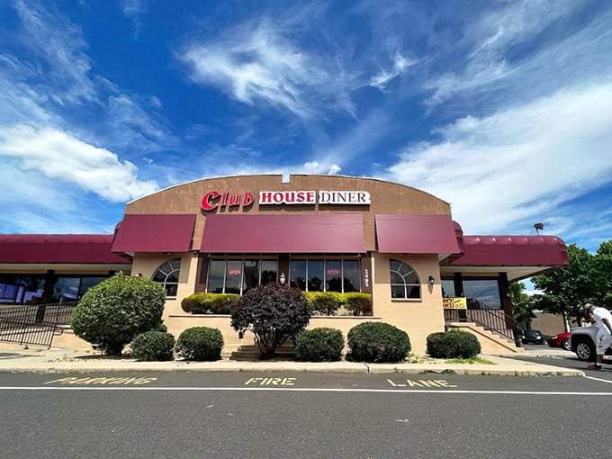 The Club House Diner stands proudly against a brilliant blue Pennsylvania sky, its burgundy awnings beckoning hungry travelers like a culinary lighthouse in Bensalem.