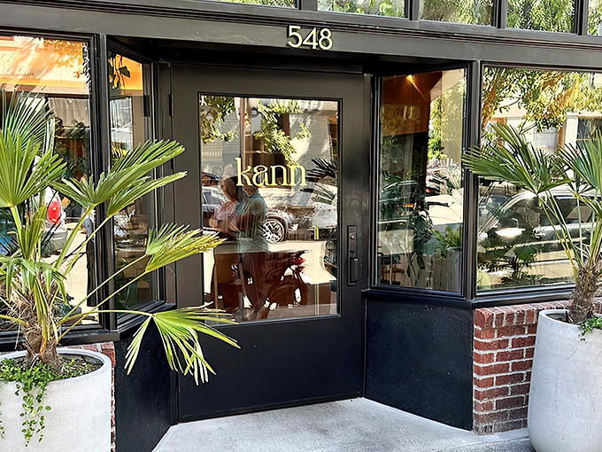 Kann's sleek exterior beckons with tropical palm sentinels standing guard. The modern black façade with "548" prominently displayed offers a stylish Portland welcome.