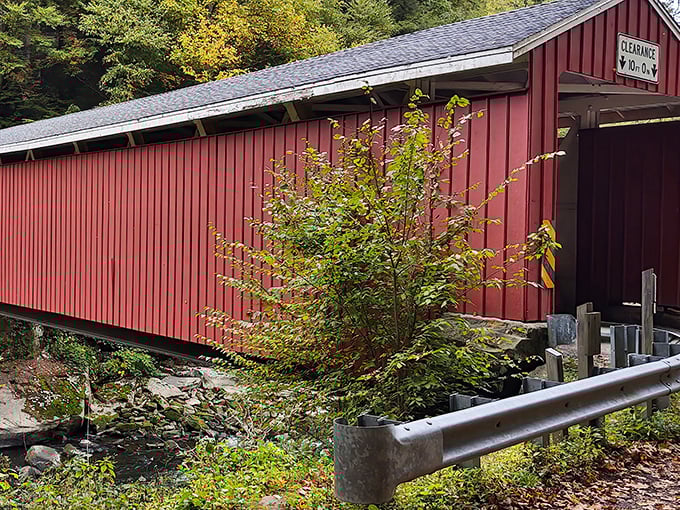 The iconic red exterior of McConnell's Mill Covered Bridge stands in striking contrast to the lush Pennsylvania wilderness, a crimson sentinel guarding Slippery Rock Creek since 1874.