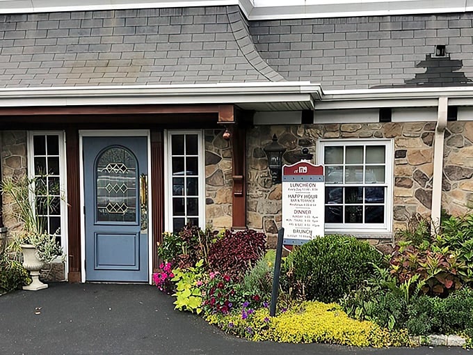 The welcoming entrance to Spring House Tavern, where colorful flower beds frame the stone facade like nature's own welcome mat.