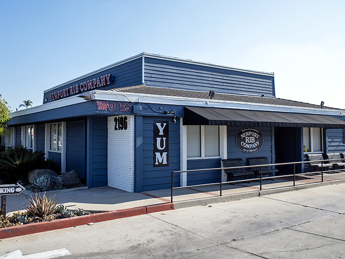 The unassuming blue exterior of Newport Rib Company hides a barbecue paradise within. That "YUM" sign isn't just decoration—it's truth in advertising.