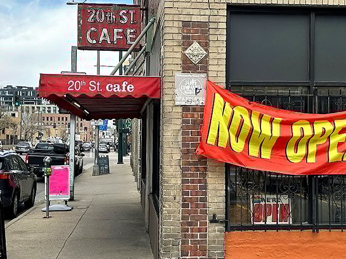 The iconic red awning and vintage sign of 20th Street Café stand as a defiant time capsule amid downtown Denver's modern landscape.