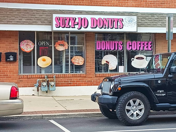 The iconic pink signage of Suzy-Jo Donuts beckons from the brick storefront like a beacon of sugary hope in a world that desperately needs more frosting.