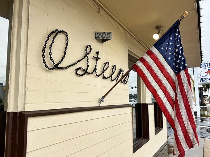 The American flag waves a patriotic hello outside O'Steen's, where the simple script signage promises authentic coastal dining without pretension.