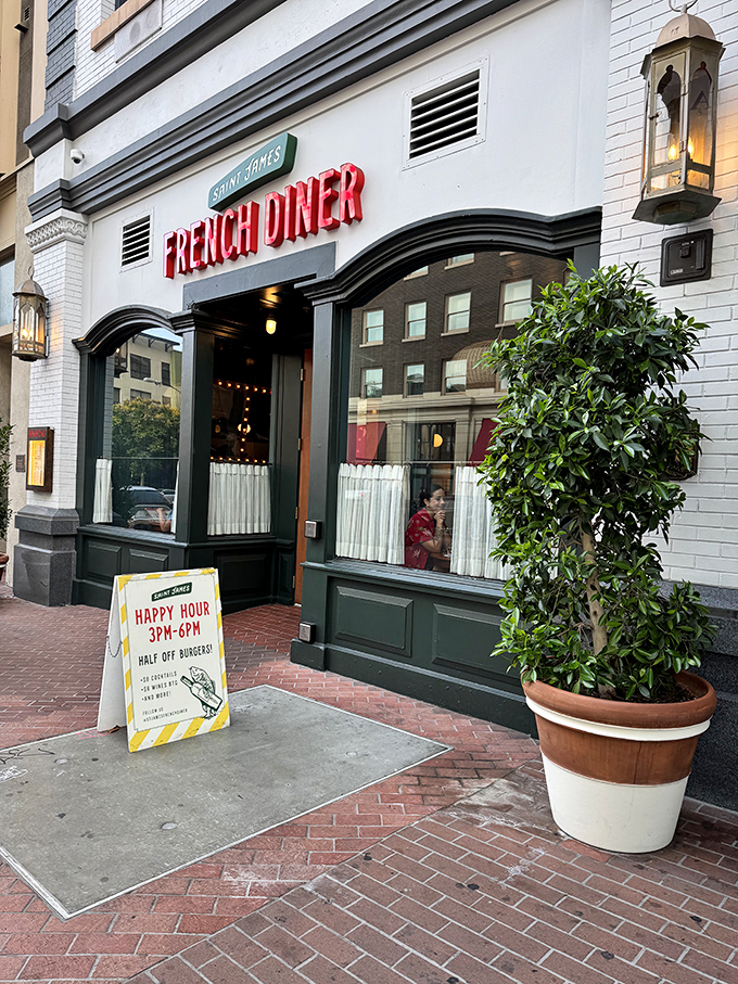 The red neon "FRENCH DINER" sign beckons like a lighthouse for the food-obsessed. Classic white brick, green trim, and that happy hour sign promising half-price burgers—resistance is futile.