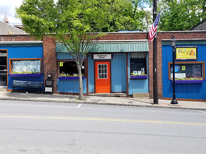 The unassuming blue exterior with that bright orange door is like a secret handshake – those who know, know this is where breakfast dreams come true.