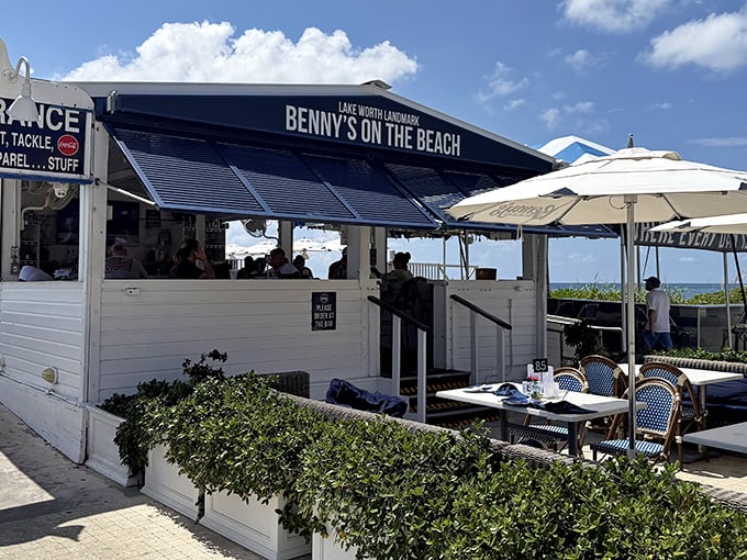 Benny's white beach shack exterior with blue awnings isn't trying to impress you—until you taste what's inside and realize you've found Florida's seafood mothership.