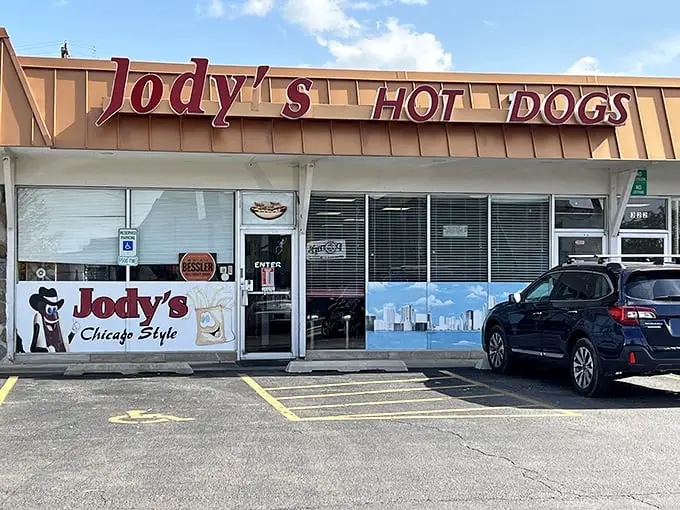 The unassuming storefront of Jody's Hot Dogs in Joliet—where culinary magic happens behind that Chicago skyline window decal.
