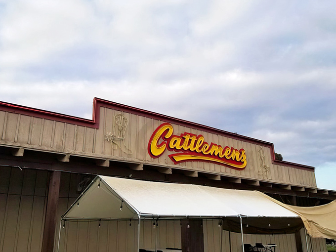 The iconic yellow Cattlemens sign beckons hungry travelers like a beacon of beef-related hope. Those wagon wheel doors promise Western hospitality and serious steak business inside.