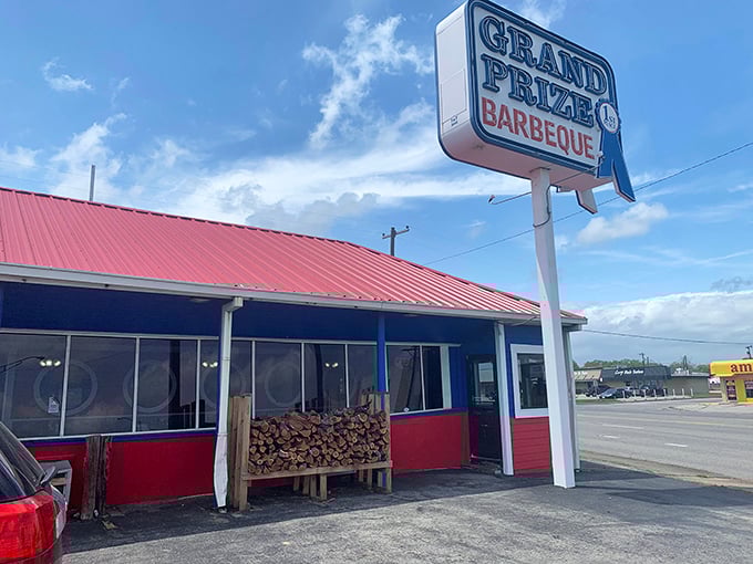 That iconic red roof and blue trim announces you've arrived at barbecue heaven. The woodpile isn't decoration—it's a promise.