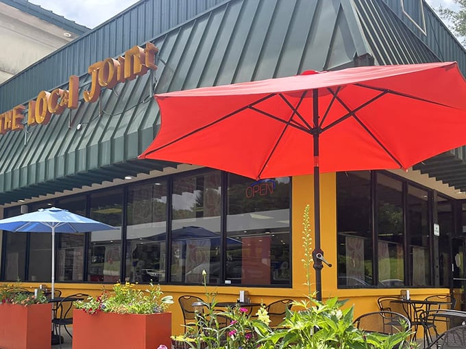 The Local Joint's exterior welcomes you with cheerful yellow accents and colorful umbrellas – like a culinary lighthouse beckoning hungry travelers to safe harbor.