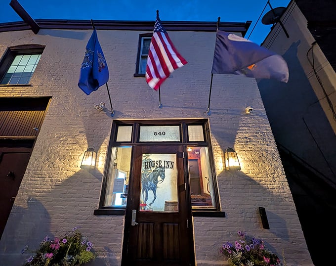The white brick façade of Horse Inn glows with welcome, flags fluttering above like a beacon to hungry travelers seeking culinary adventure in Lancaster.