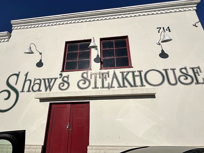 The white facade with bold green lettering and red doors isn't just a restaurant entrance—it's a portal to California's beef heritage.
