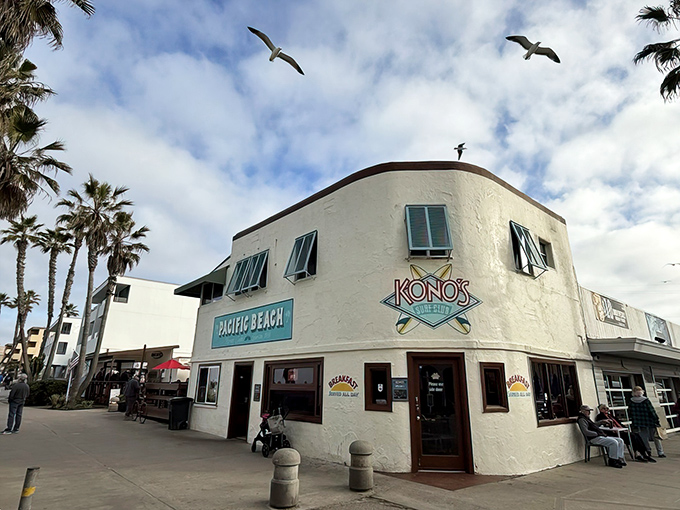 The iconic white-washed corner of Kono's stands like a beacon for breakfast pilgrims, with palm trees and seagulls completing the quintessential San Diego scene.