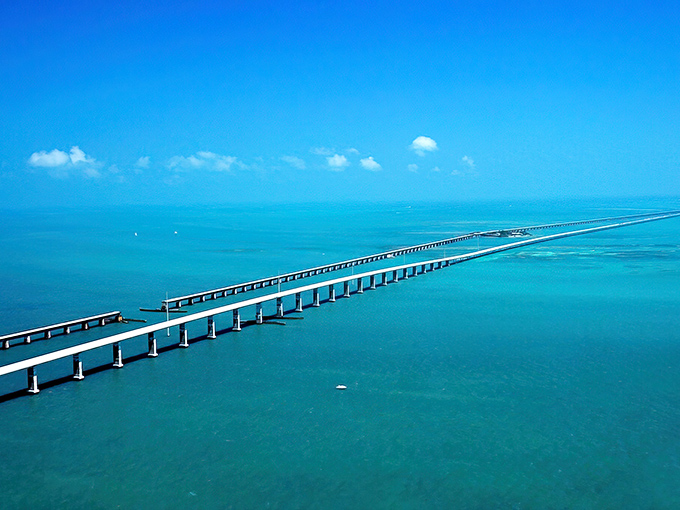 Where the sky meets the sea meets engineering marvel—the Seven Mile Bridge stretches across impossibly turquoise waters, with Pigeon Key nestled like a green jewel below.