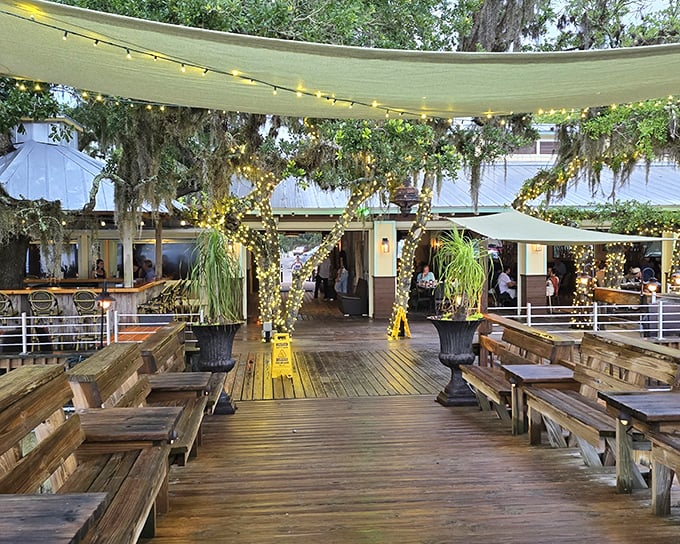 The outdoor deck at Cap's transforms into a magical wonderland at dusk, where string lights and Spanish moss create nature's perfect dining canopy.