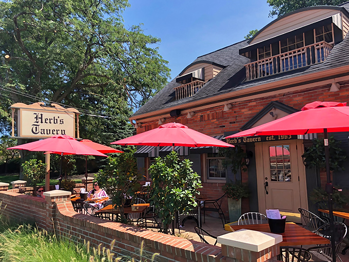 Herb's Tavern welcomes you with classic brick charm and cheerful red umbrellas – like finding a neighborhood gem you've been missing your whole life.
