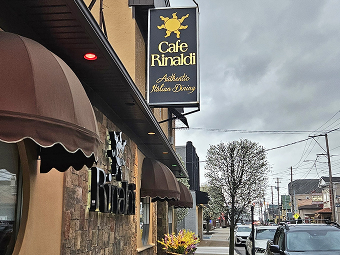 The welcoming façade of Cafe Rinaldi beckons with its stone exterior and distinctive burgundy awnings – Old Forge's culinary beacon on a cloudy Pennsylvania day.