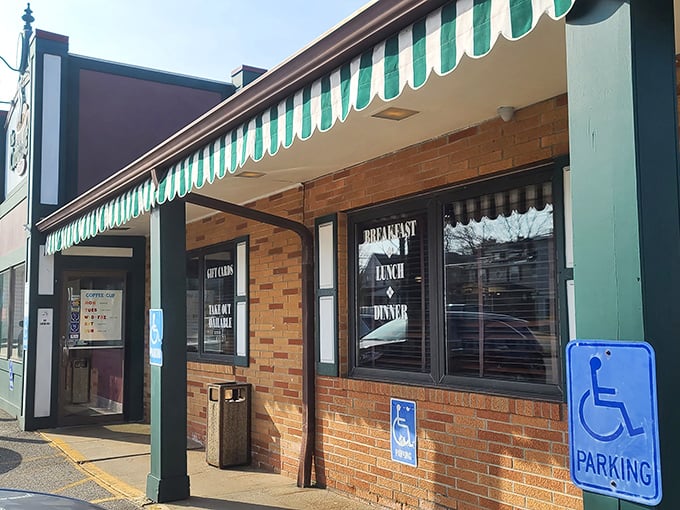 The green and white striped awning beckons like an old friend, promising comfort food treasures behind that unassuming brick facade.