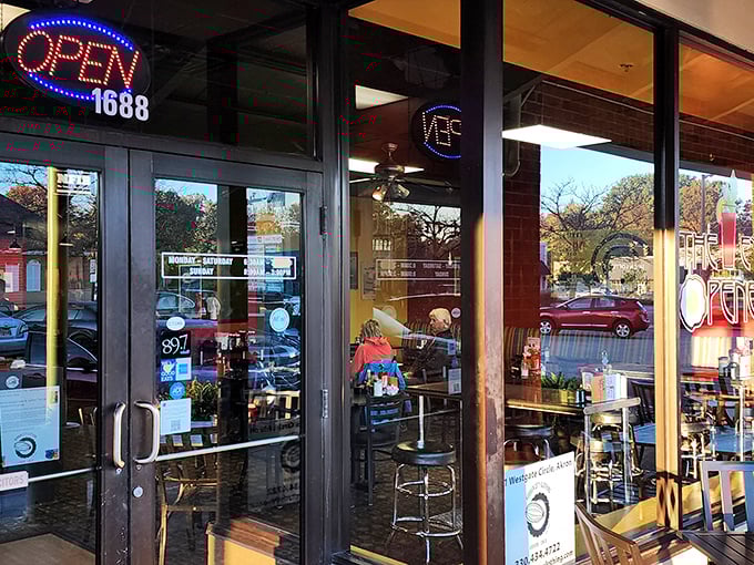 The welcoming storefront of The Eye Opener beckons with its distinctive sign and cozy patio seating—breakfast paradise awaits behind those doors.