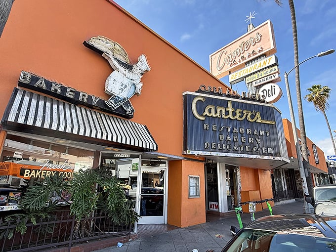 The iconic orange facade of Canter's Deli stands like a beacon on Fairfax Avenue, promising delicious salvation to hungry Angelenos 24 hours a day.