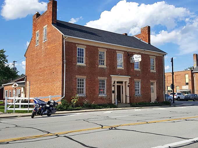 The historic Red Brick Tavern stands proudly against an Ohio sky, its weathered facade whispering tales of presidential visits and centuries of hungry travelers.