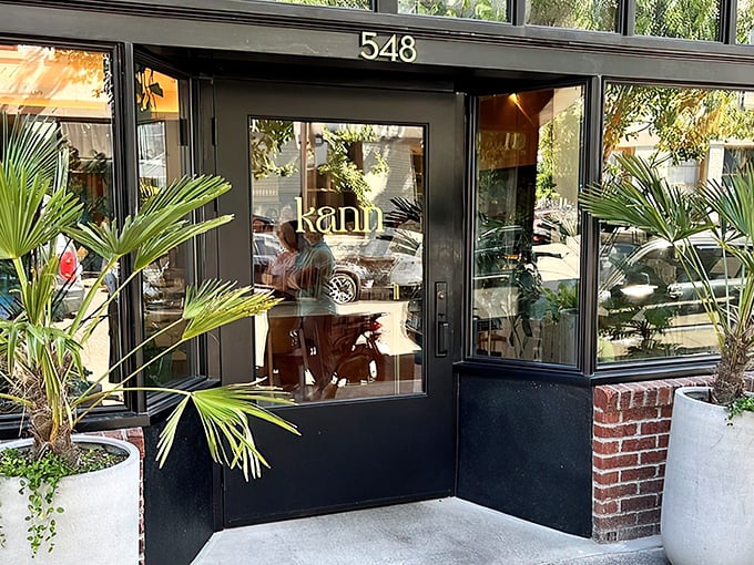 Kann's sleek exterior beckons with tropical palm sentinels standing guard. The modern black façade with "548" prominently displayed offers a stylish Portland welcome.