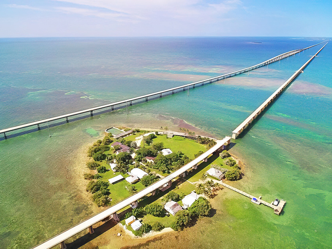 Where the sky meets the sea meets engineering marvel—the Seven Mile Bridge stretches across impossibly turquoise waters, with Pigeon Key nestled like a green jewel below.