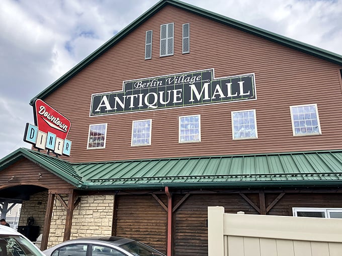 The barn-like exterior of Berlin Village Antique Mall stands proudly against an Ohio blue sky, its distinctive green roof and cupolas beckoning treasure hunters from miles around. 