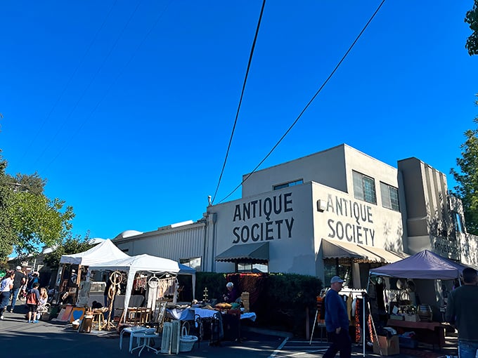 The iconic white facade of Antique Society stands proudly against the California blue sky, with outdoor vendors creating a festive marketplace atmosphere.