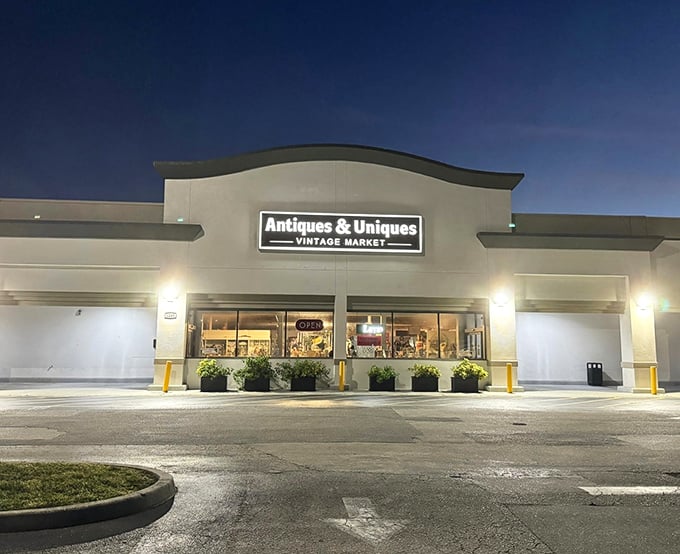 The unassuming storefront of Antiques & Uniques transforms into a wonderland after dark, beckoning treasure hunters with its warm glow against the Florida night.